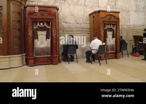 several seated men praying in a prayer room at the western wall of the ...