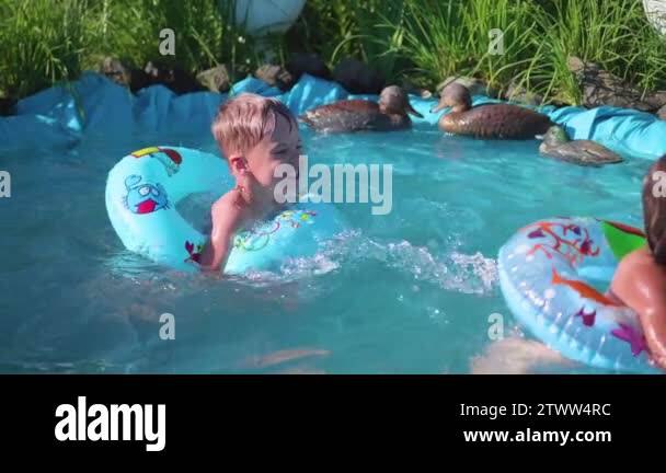 Two small children swim in a small pond. Brother and sister laughing ...
