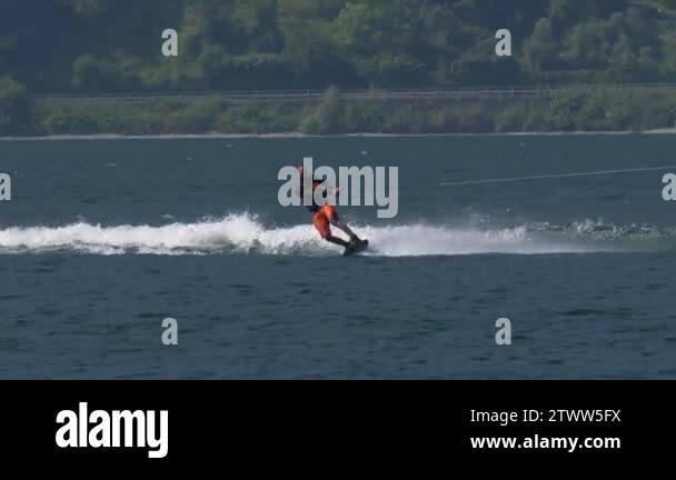 A boy riding wakeboard on wave of motorboat and jumping the wake during ...