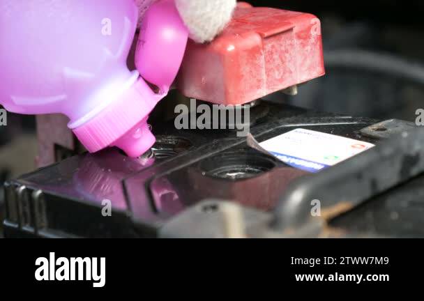 Close up shot hands of mechanic pouring distilled water refill to car ...