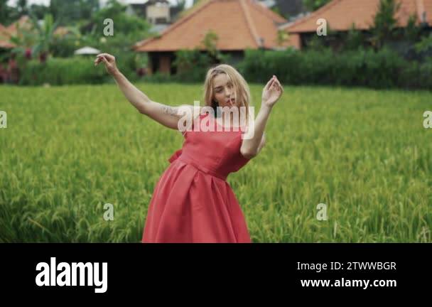 Dance in slow motion, a young girl in a red long dress is like hiding ...