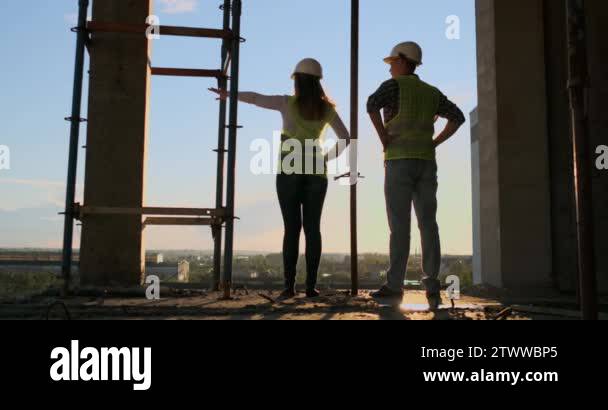 Woman architect and man builder at construction site, back view ...