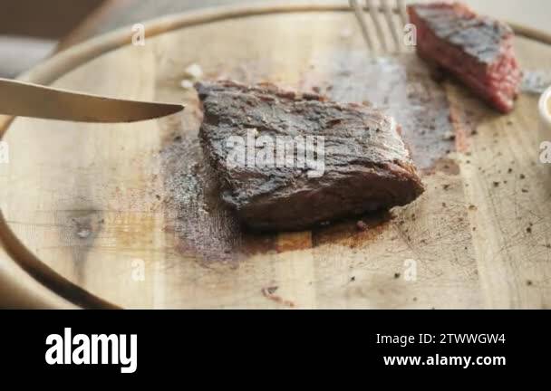 the man in the restaurant with a knife cuts steak of marble beef ...
