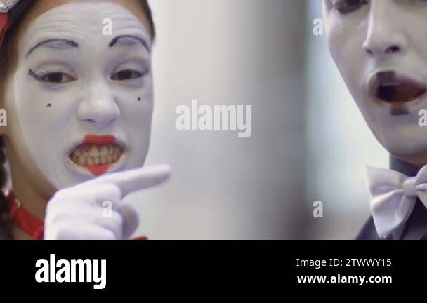 Two funny mimes play a scene. Girl and guy gesticulates their facial ...