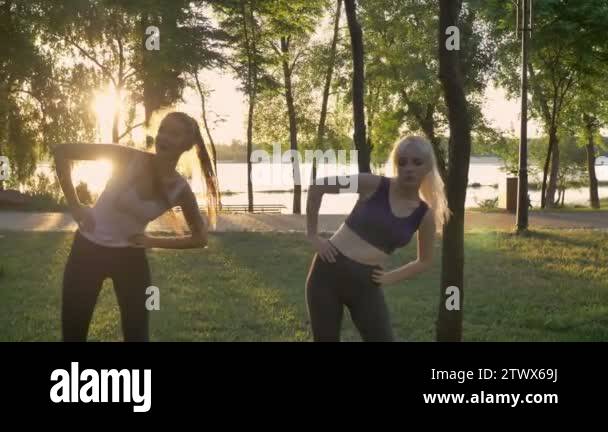 Two young womans doing aerobics in park, weight loss, fitness models ...