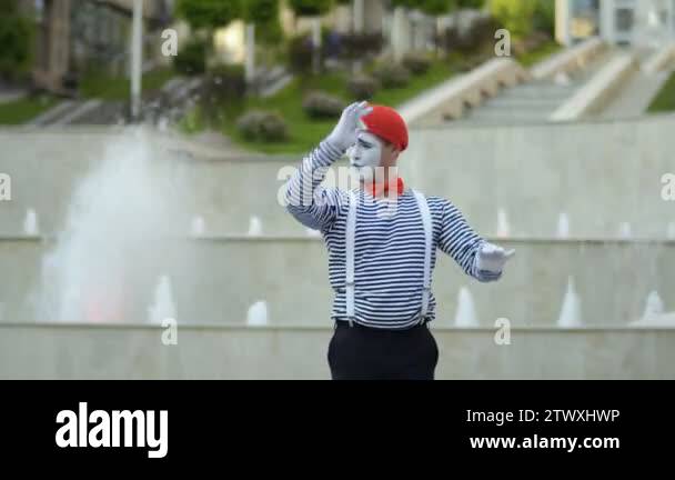Funny mime in red beret has a performance at fountain bakcground and ...