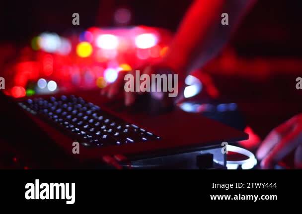 Laptop with mixing program and DJ mixer lights in the dark. Disc jockey ...