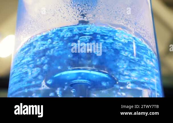 Boiling water in large glass cooler with a neon backlight and metal ...