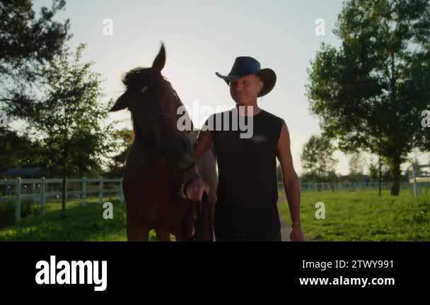 SLOW MOTION CLOSE UP: Senior man leading his stallion by the reins ...