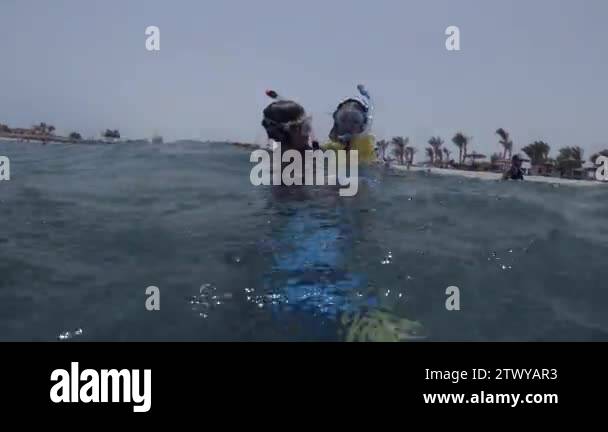 Woman and little boy in mask, snorkel and fins play in water ...