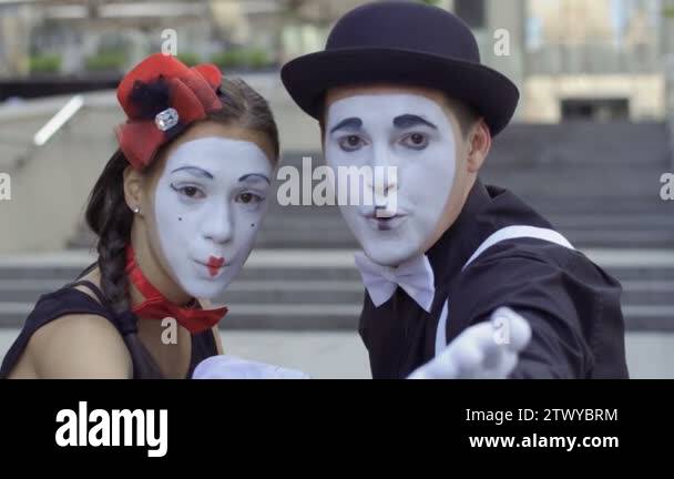 Two funny mimes play a scene. Girl and guy gesticulates their facial ...