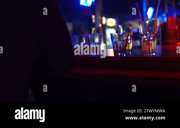 Drunk man smoking cigarette near bar counter with empty glasses, bad ...