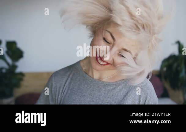 A woman of natural beauty with white hair and red lipstick laughs and ...