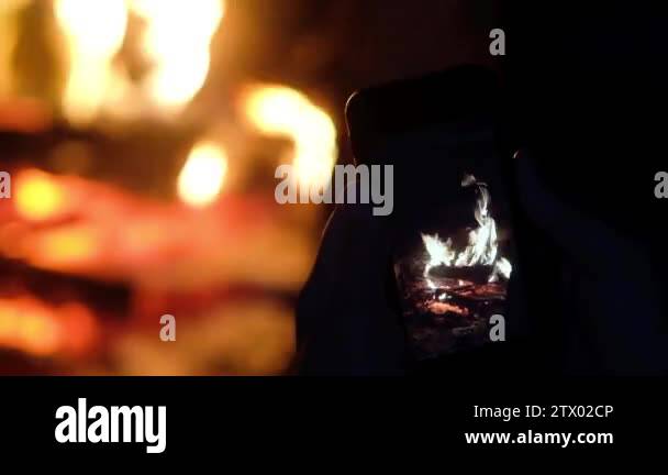 man records a video of a burning fire with a hot flame in the fireplace ...