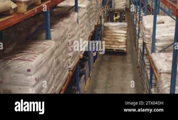 Elevated front view of a forklift truck driving down a corridor between ...