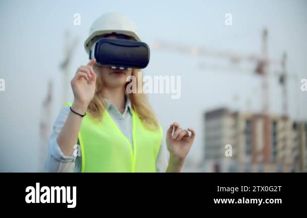 Woman designer on a building site in hard hat and vest in the glasses ...