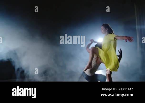 Zoom camera, two modern ballet dancers are dancing on stage in smoke a ...