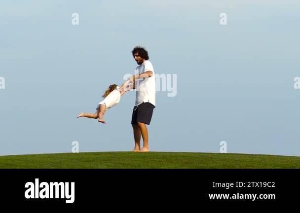 Father holding hands daughter and whirl around himself. Having fun ...