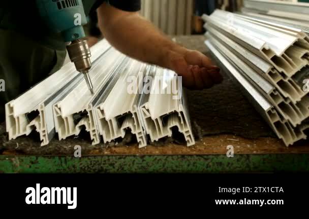 Production of pvc windows, the worker screws a metal profile to the ...