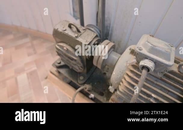 An old electric motor covered with dust and dirt turns a two-thread ...
