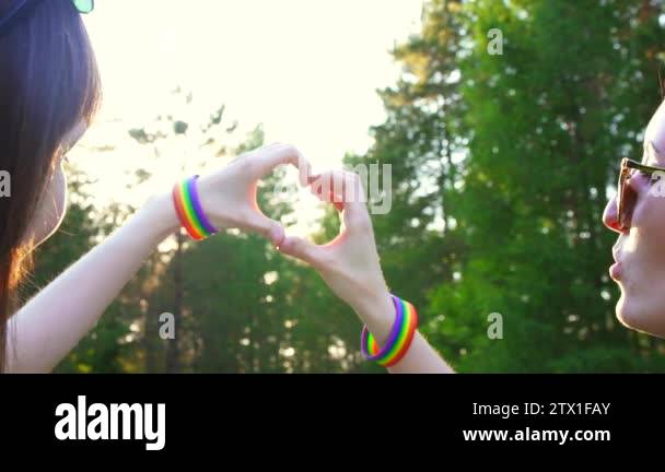 two girls make heart hands at sunset,the sun,the symbol of LGBT people ...