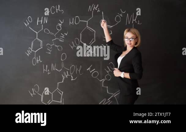 Teacher writing formulas on the chalk Board and explains the students ...