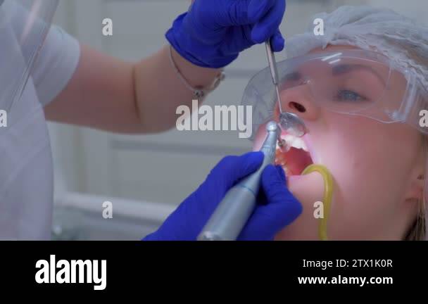 Dentist cleaning brushing and polishing womans teeth uses drill ...