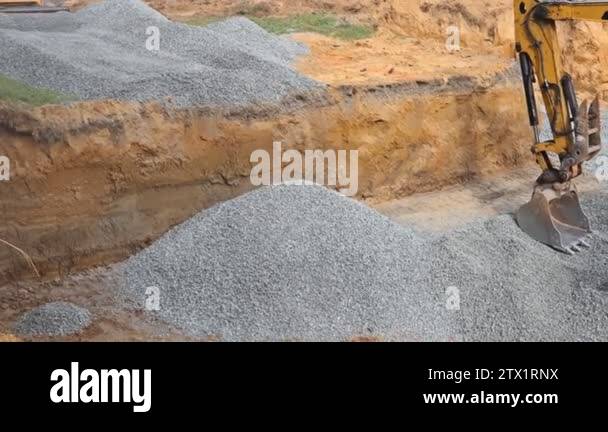 Excavator bucket backfilling trench for stone backfill of foundation ...