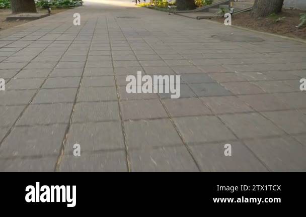 movement along a paved pedestrian walkway. unrecognizable people walk ...
