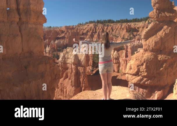 Young woman traveler standing at viewpoint in Bryce Canyon, raising her ...
