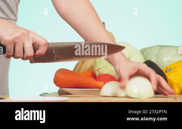 a female hand is cut with a knife an onion. mixture of vegetables for ...