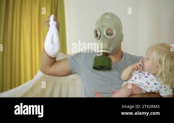child and the man in a gas mask with disgust holding a diaper Stock ...