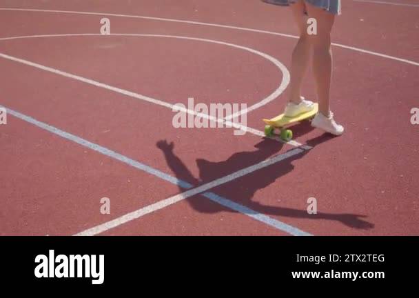 Slim female legs in white sneakers girl riding yellow skateboard on an ...