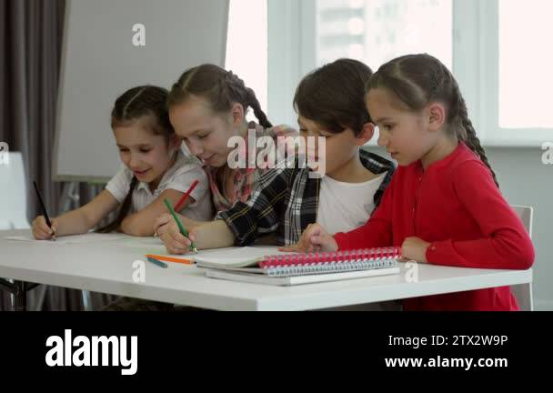 Four children draw together. Three girls and one boy try to paint ...
