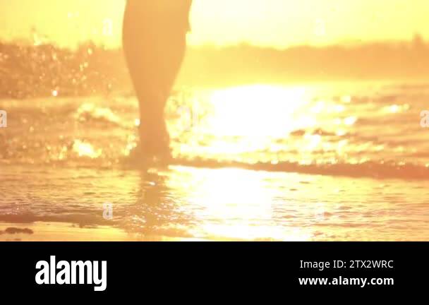 SLOW MOTION CLOSE UP LENS FLARE: Active young man running on sandy ...