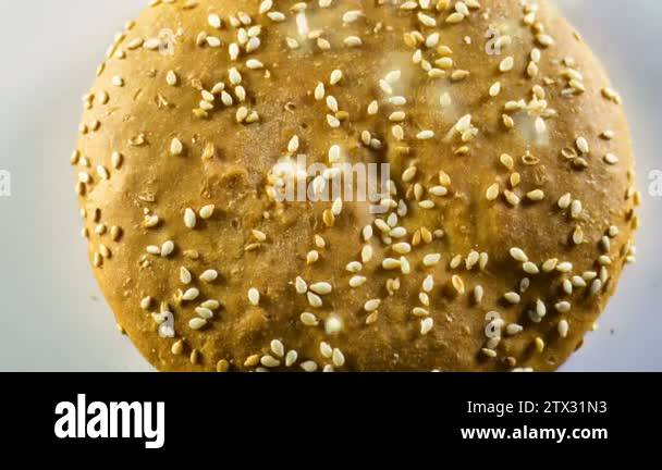 top view of a round bun that rotates and onto which falls sesame, a ...