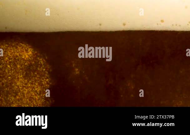Close up background of pouring lager beer with bubbles and froth in ...