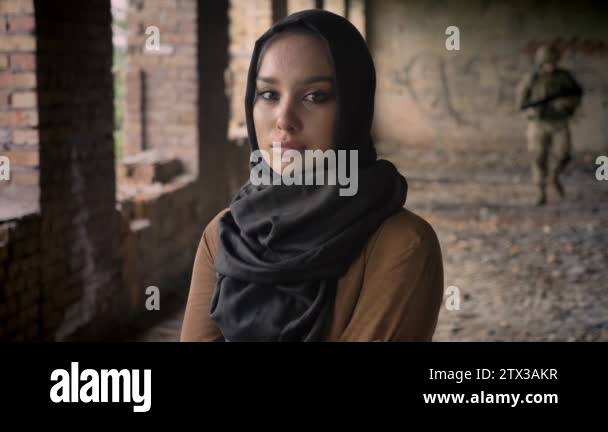Young sad muslim woman in hijab, soldier with gun and ammunition ...