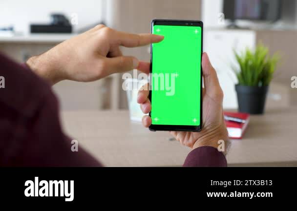 Man hand scrolling down on a smartphone with green screen chroma mock ...