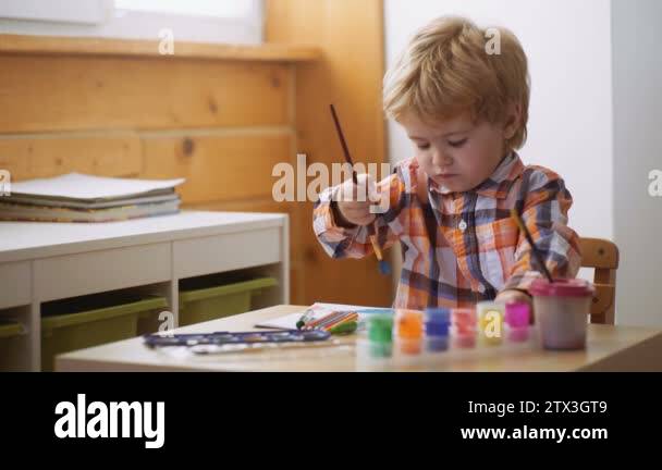 Creativity and education concept. Drawing. Happy cute boy colors his ...