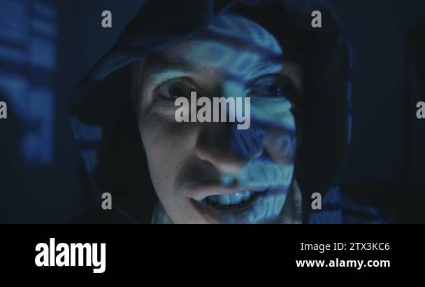 Close up of Crazy hacker programmer in hood with binary code reflection ...