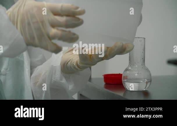Chemist pouring viscous liquid into a flask. The scientist preparing ...