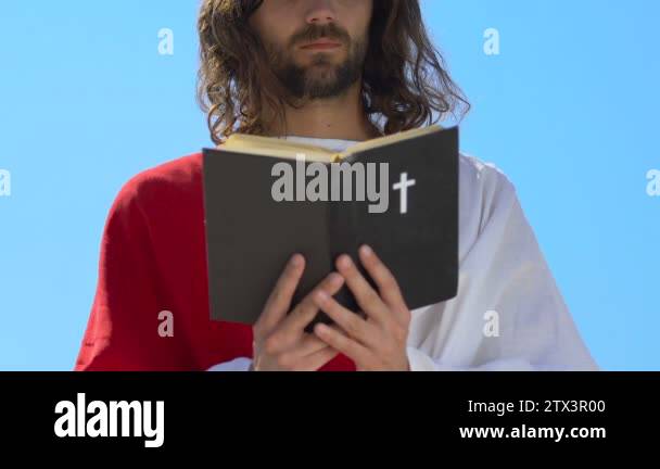 Jesus in robe reading Holy Bible and praying God with eyes closed ...