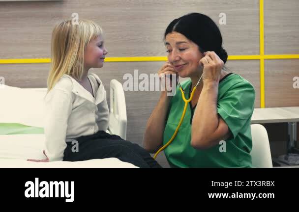Friendly doc. Cheerful senior female pediatrician using stethoscope ... Friendly doc. Cheerful senior female pediatrician using stethoscope ...