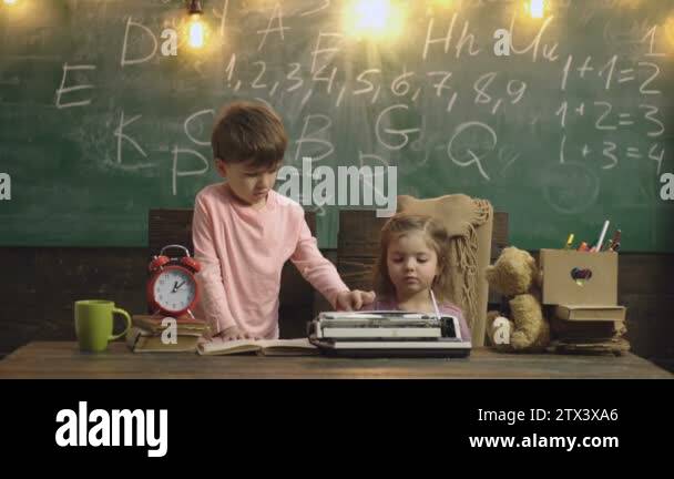Preschool boy and girl learning to type on typewriter in school ...
