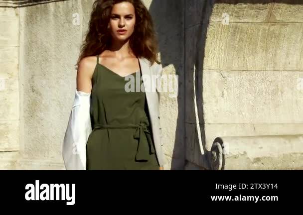 Pretty smiling curly woman in stylish look confidently walks down the ...