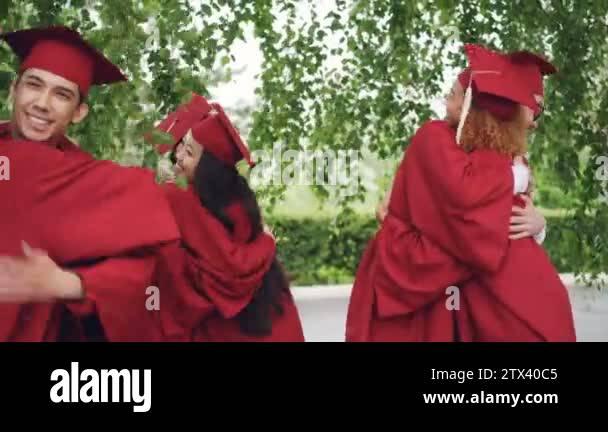 Joyful friends graduating students in gowns and mortarboards are ...