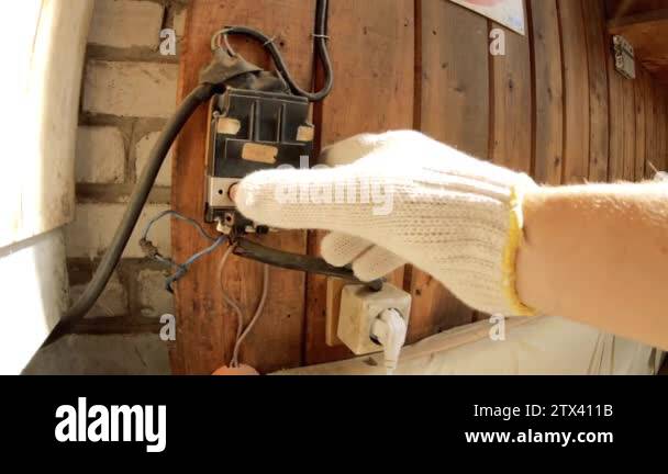 Outdated electrical switchboard and control buttons. A man turns on or ...