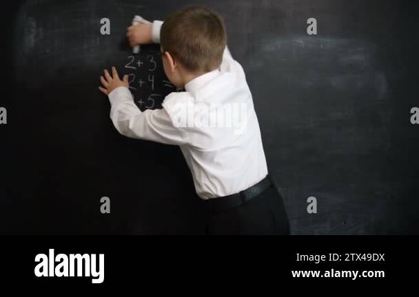 Young boy washing blackboard after solving maths expressions. Creative ...