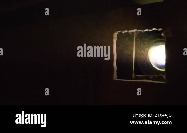 Closeup dazzling light from movie projector flows through hole ...